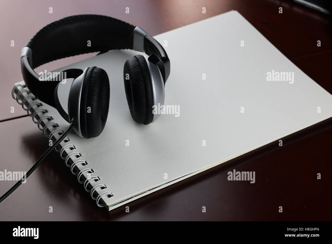 Headphones on a table next to the tablet and a clock Stock Photo - Alamy