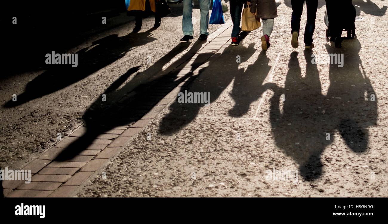 People cast long shadows on the ground while walking through Hanover ...