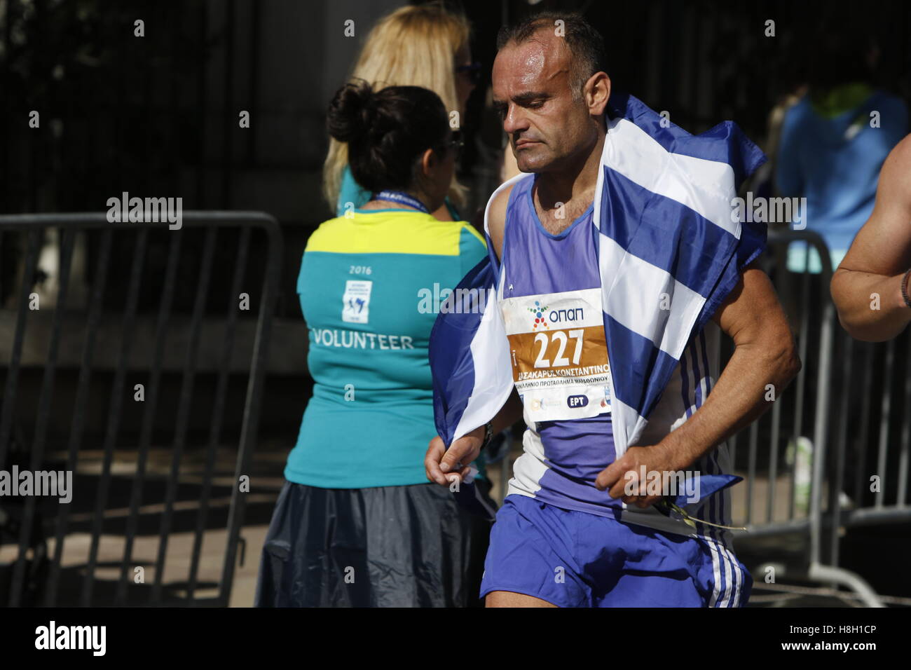 Athens, Greece. 13th November 2016. A runner is wrapped in a Greek flag ...