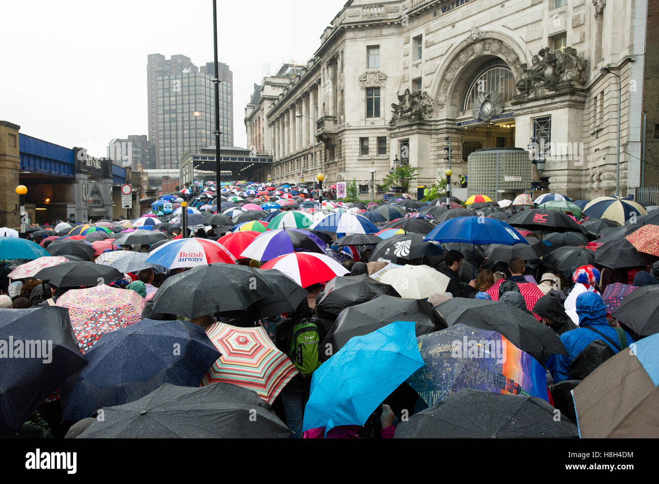 People queuing to get into Waterloo Railway station during a rain storm ...