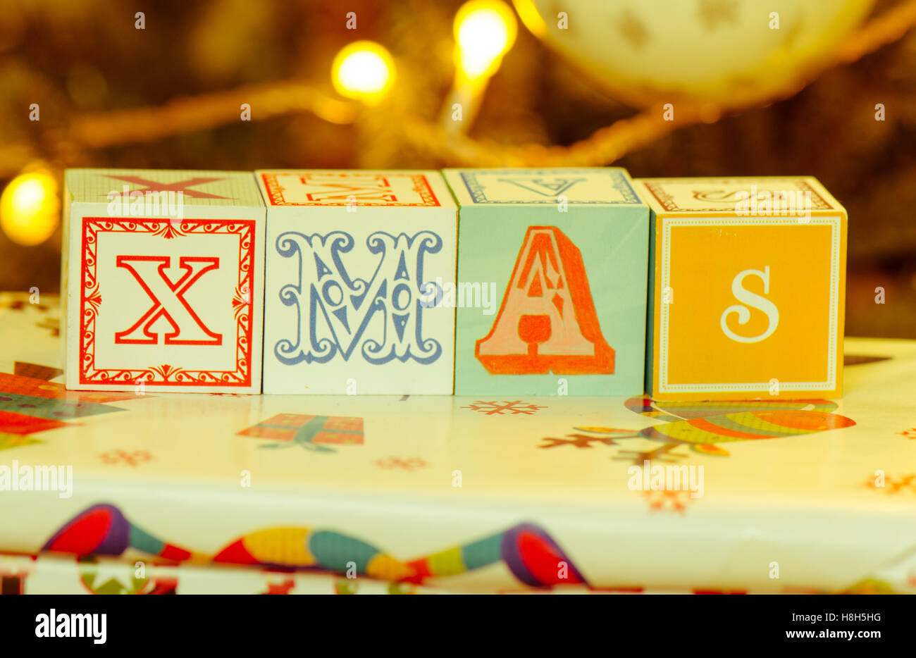 Toy letter blocks stacked on a pile of presents spell the word xmas wth ...