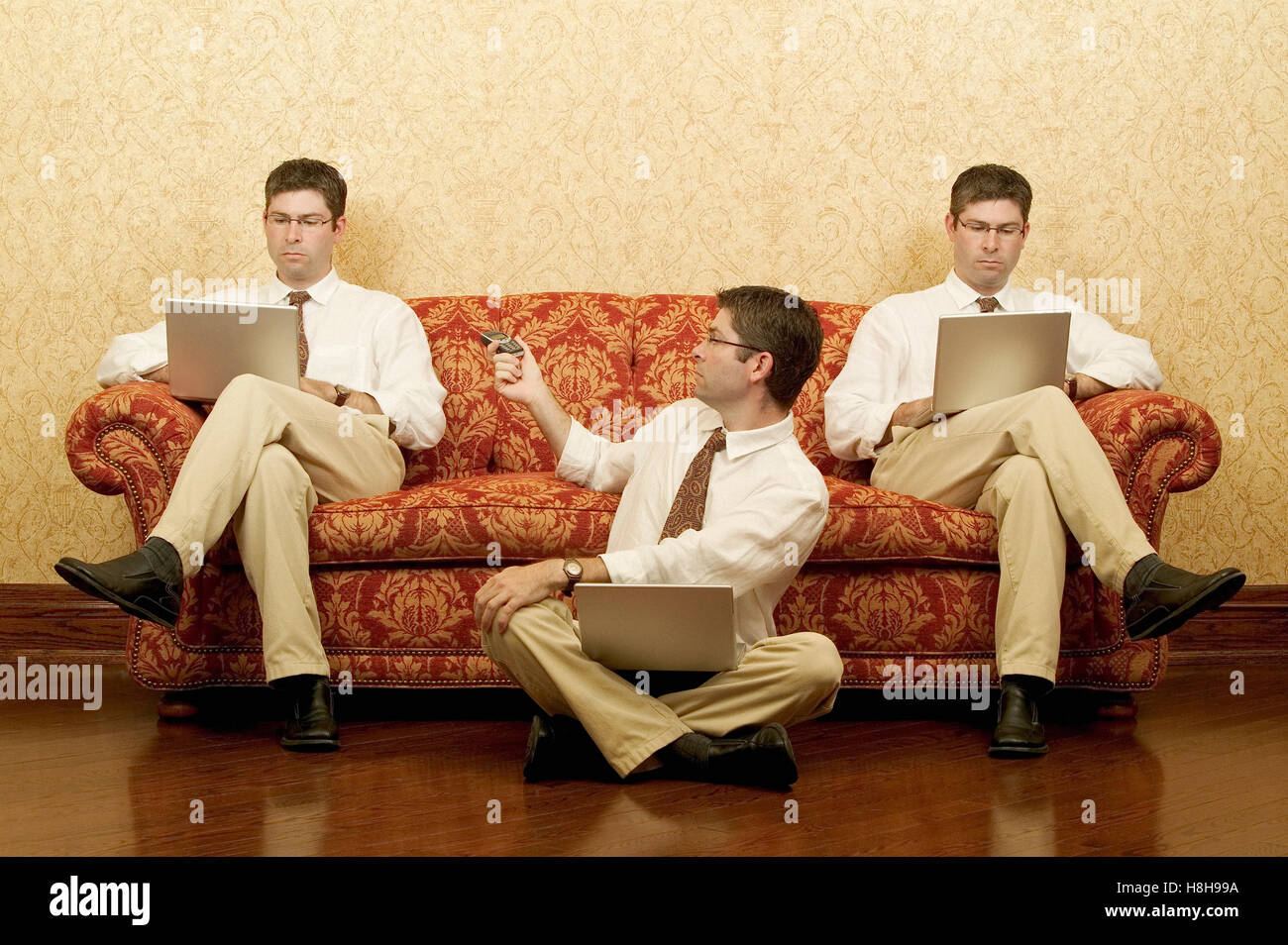 Clones sitting on a sofa working on computers Stock Photo - Alamy