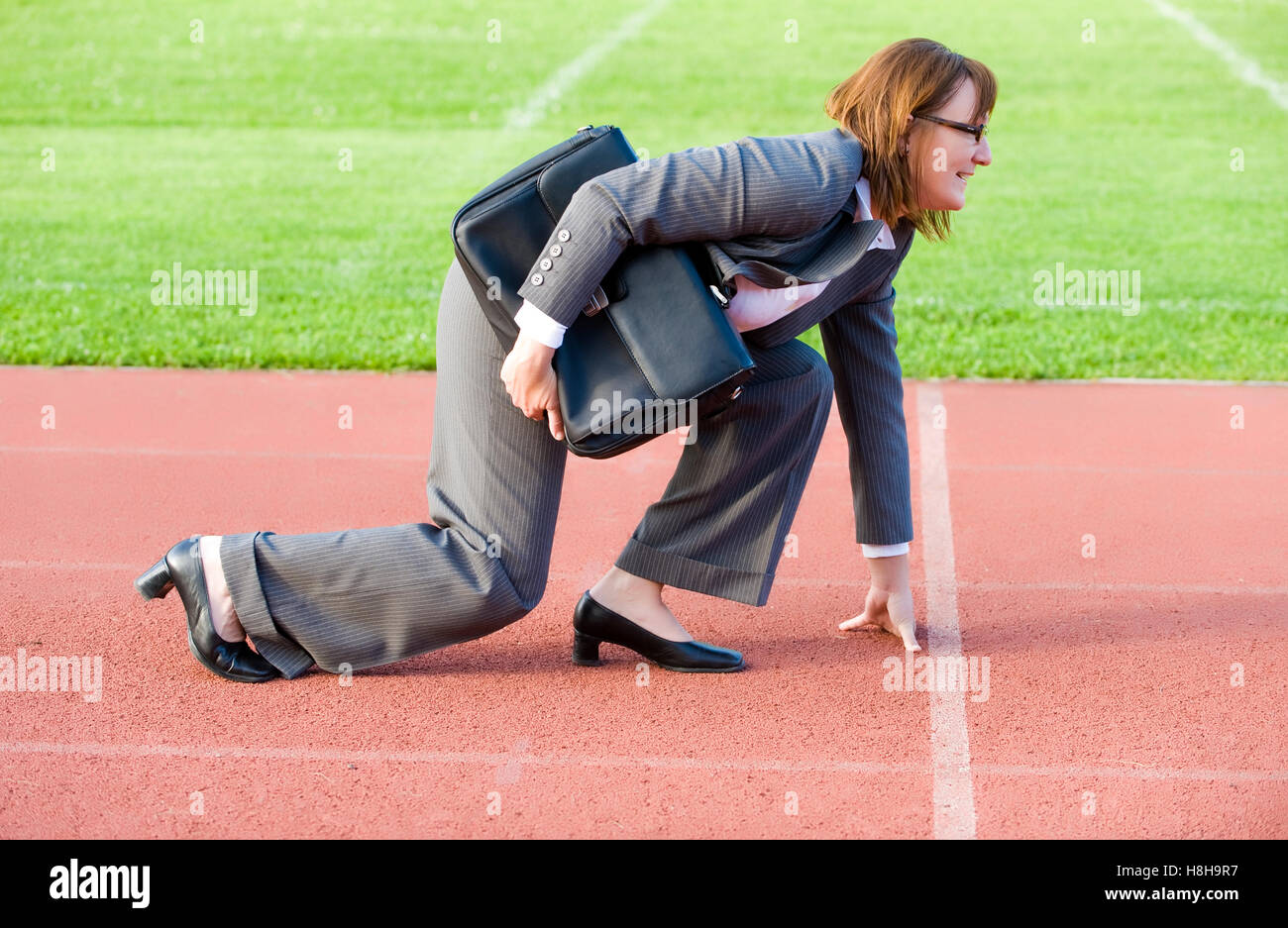 Businesswoman at starting line of a running track, symbolic of carreer ...