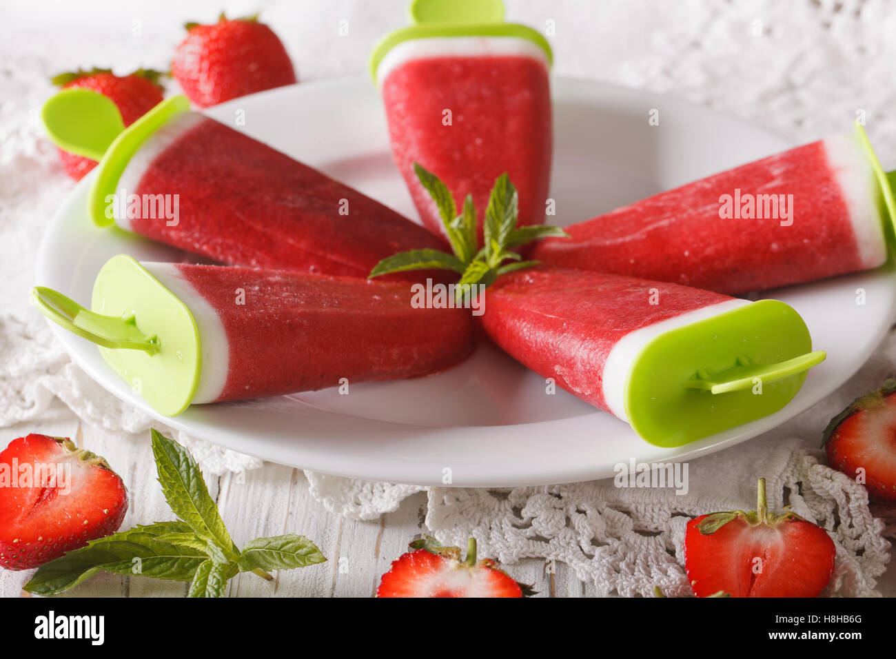 Strawberry ice cream with mint on a stick closeup on a plate ...