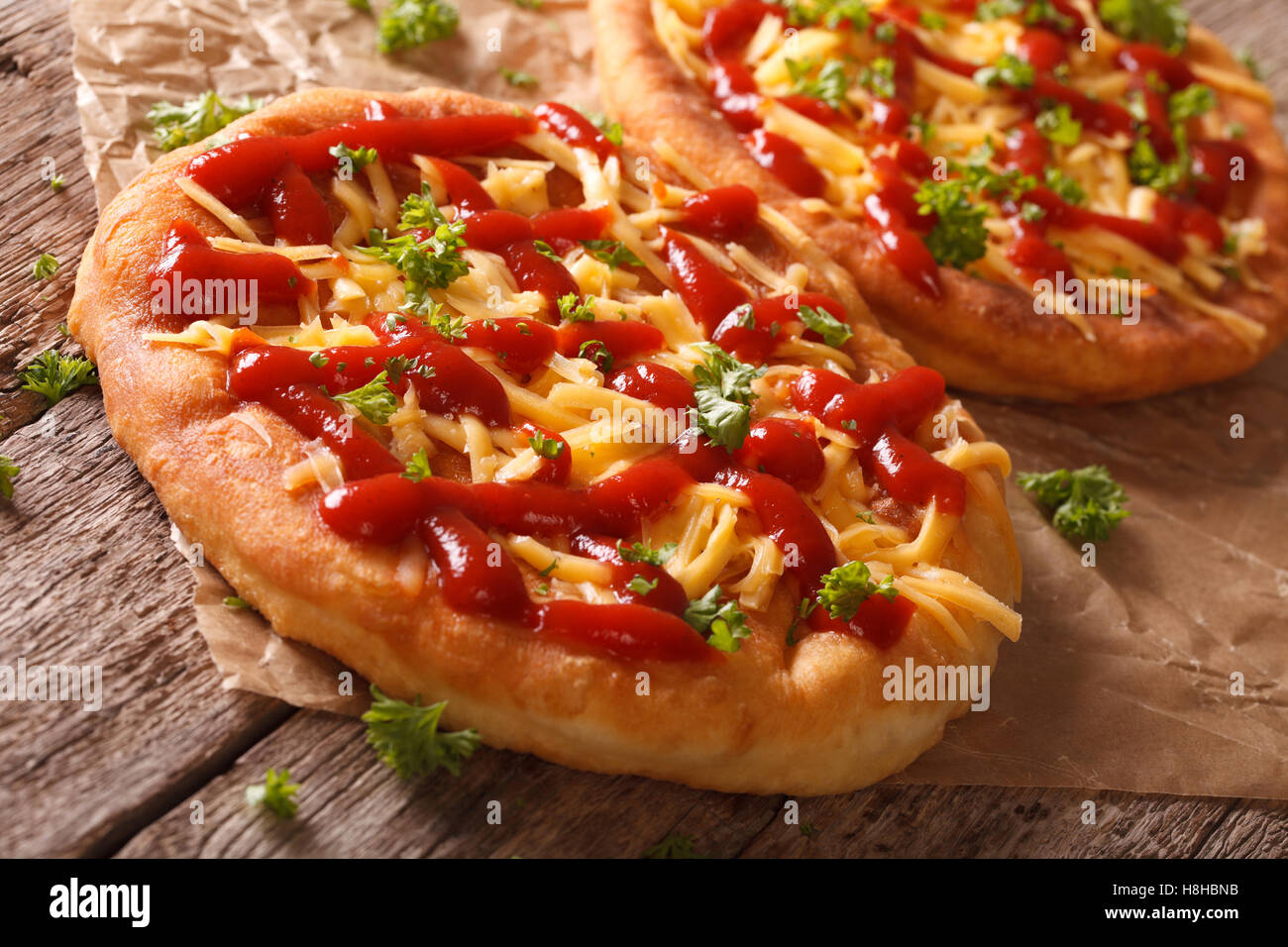 Tasty langos with cheese and ketchup on the table close-up. horizontal ...
