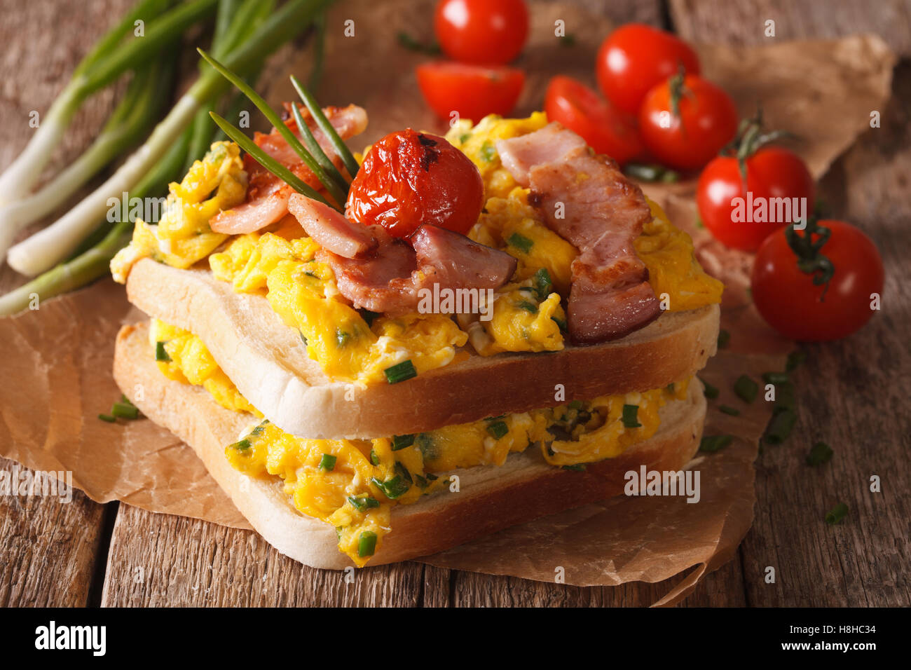 double sandwich with scrambled eggs, bacon and tomatoes close-up on the ...
