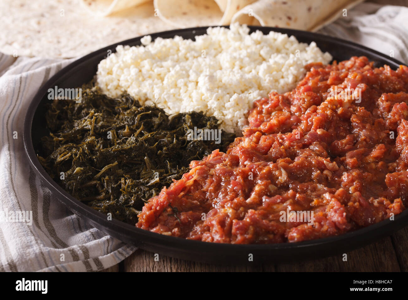 Ethiopian kitfo with herbs and cheese ayibe on a plate and injera close ...