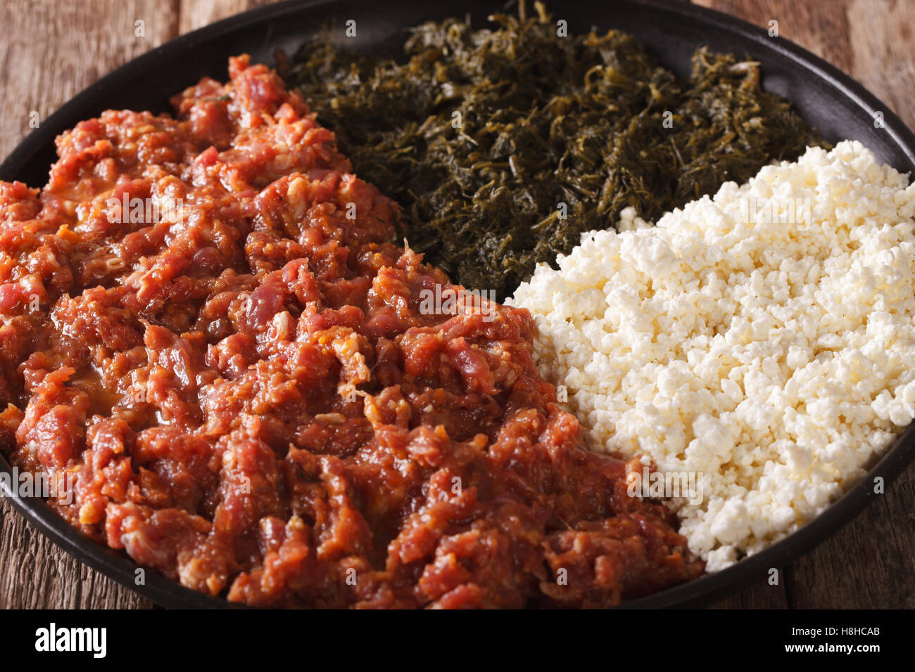 Ethiopian cuisine: kitfo with greens and cheese ayibe on a plate macro ...