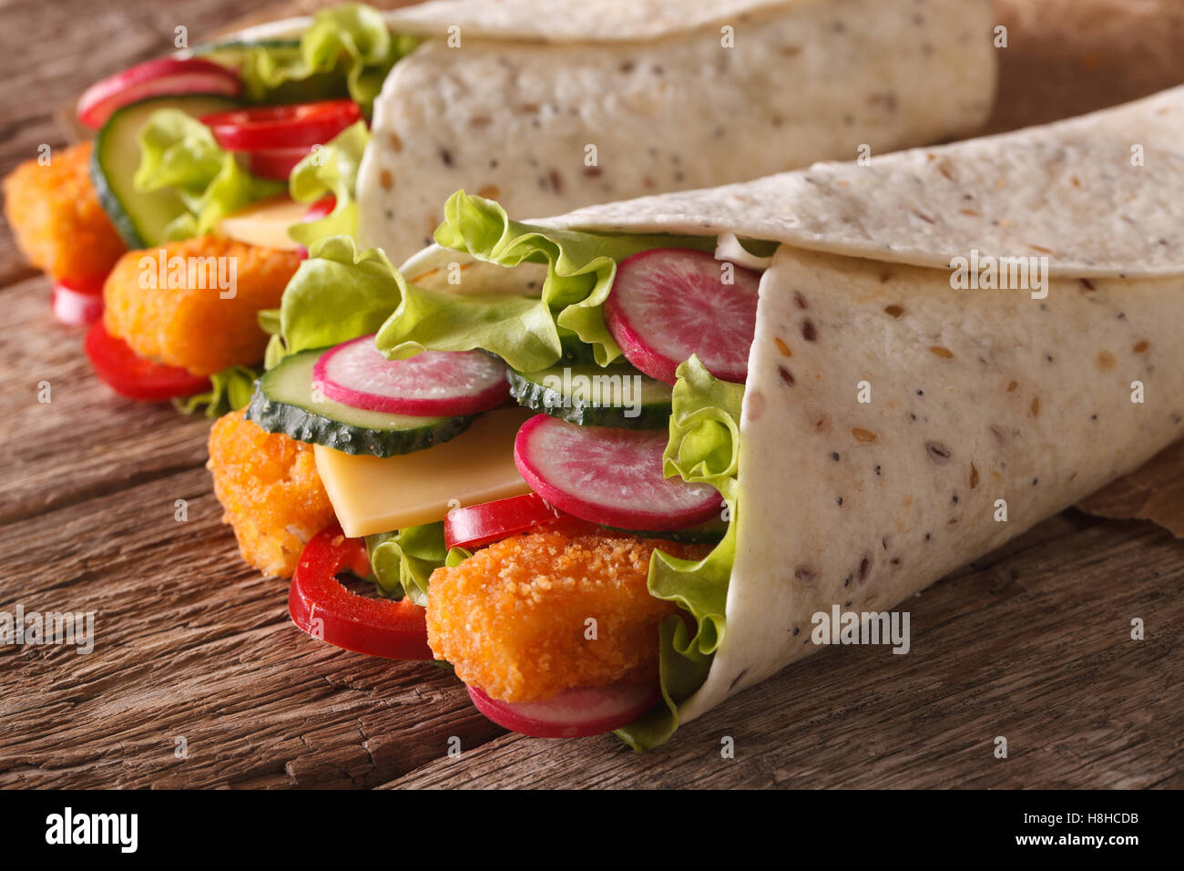Burrito with fish fingers, and vegetables macro on the table ...