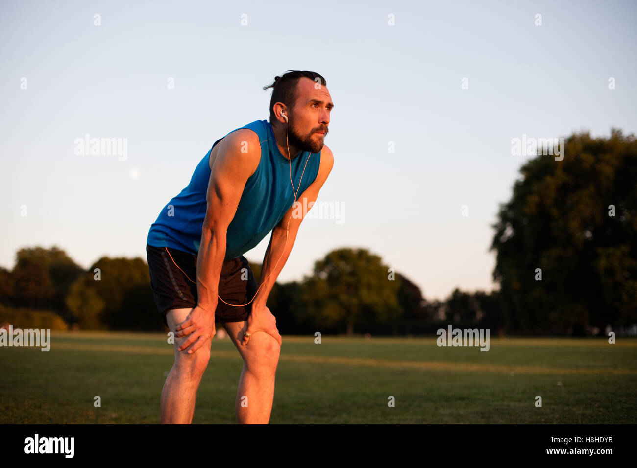 Young athletic man resting after a run in the park Stock Photo - Alamy