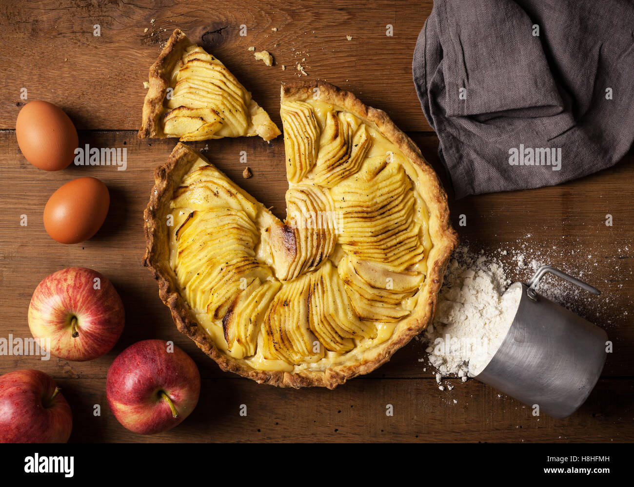 Homemade apple pie on a natural wooden table with apples, eggs and ...