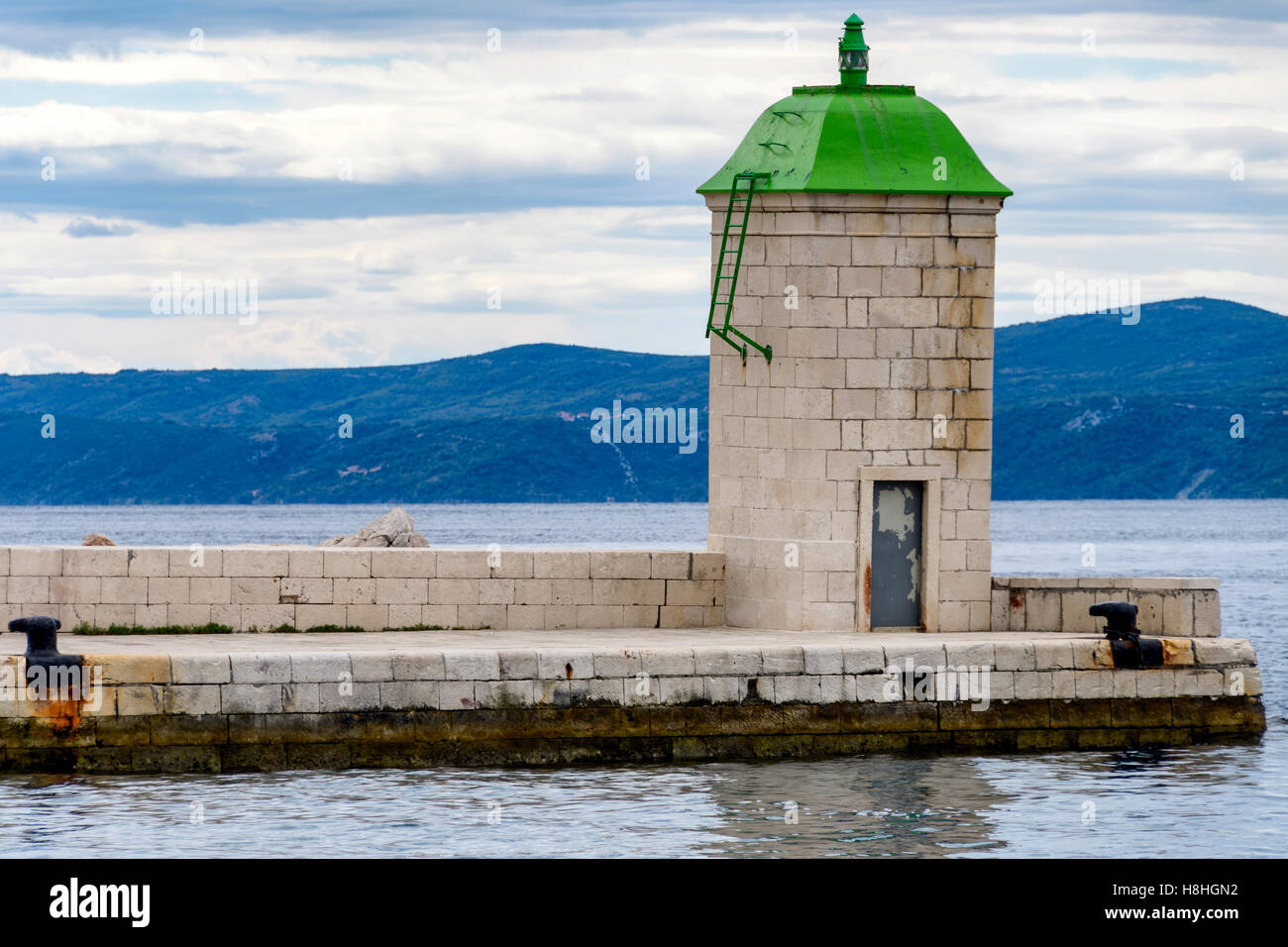 Traditional lighthouse in harbour with green roof on stone pier Stock ...