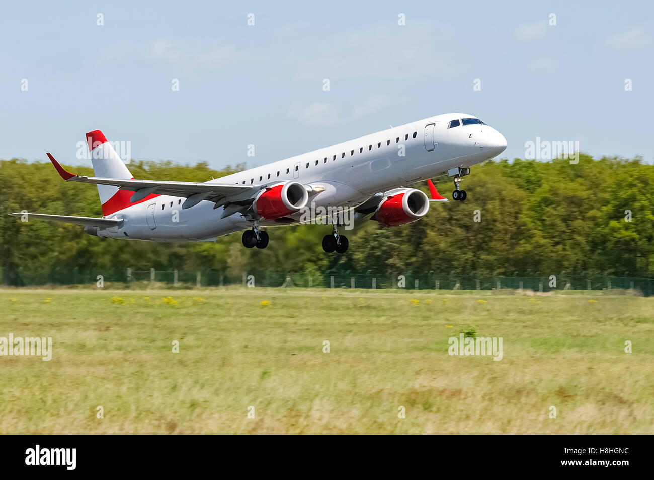 Medium sized commercial airliner with neutral livery taking off runway ...