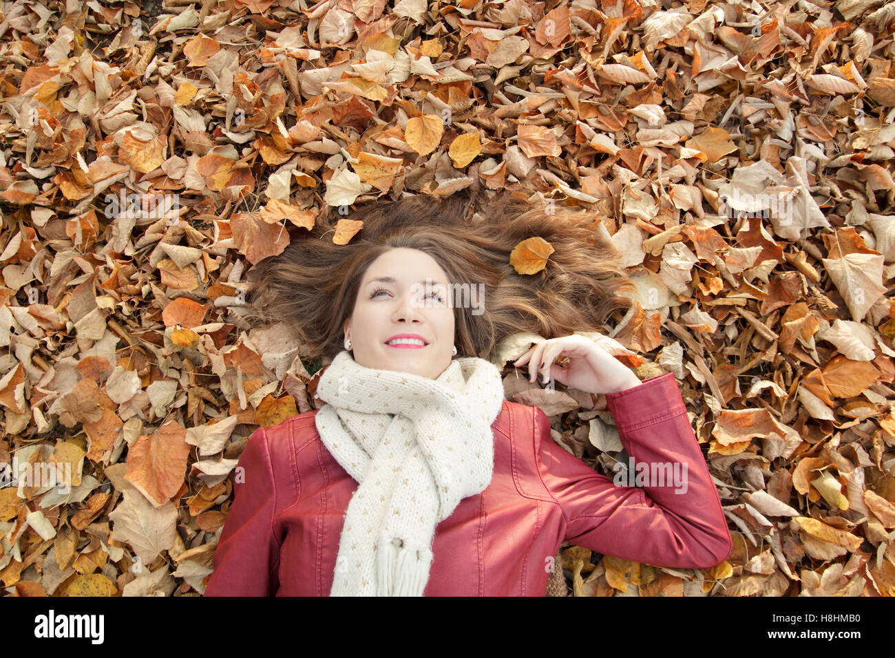 Young woman lying on fallen autumn leaves portrait Stock Photo - Alamy