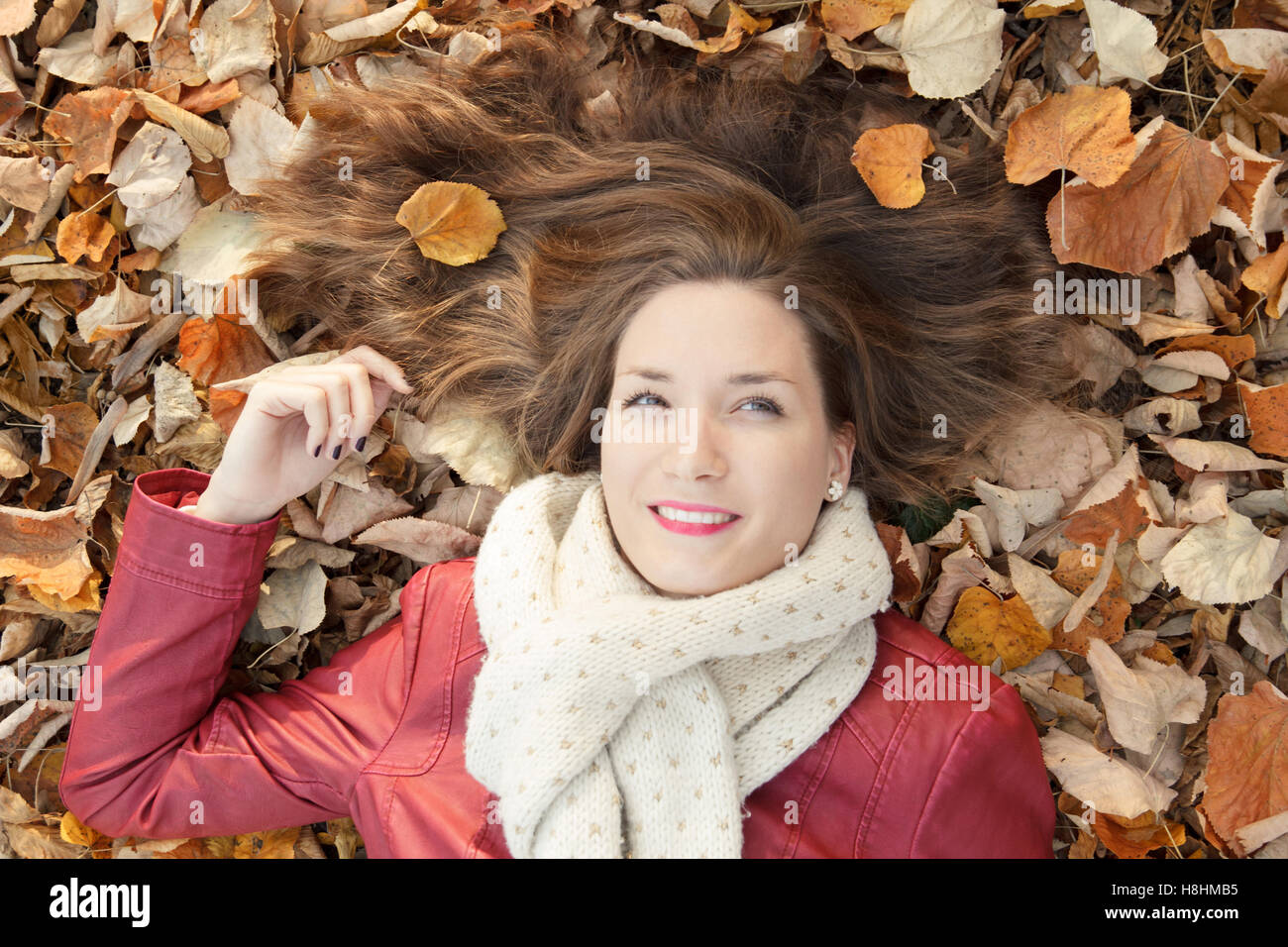 Young woman lying on fallen autumn leaves portrait Stock Photo - Alamy