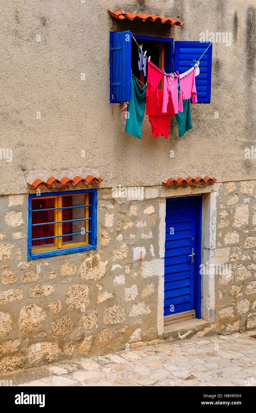 Laundry driying in sun, washing line hanging from blue windows and ...