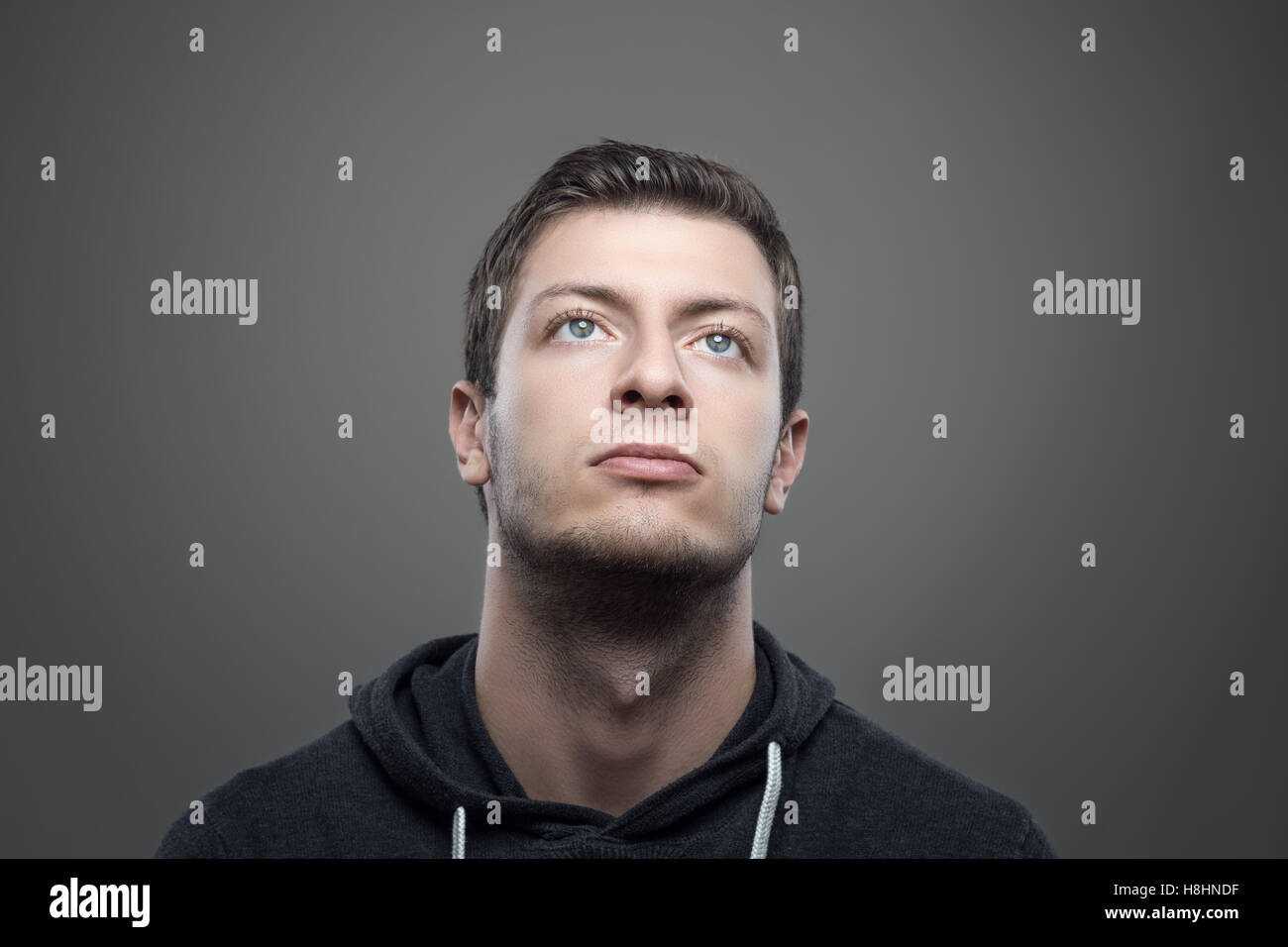 Moody portrait of young casual man looking up with illuminated face ...