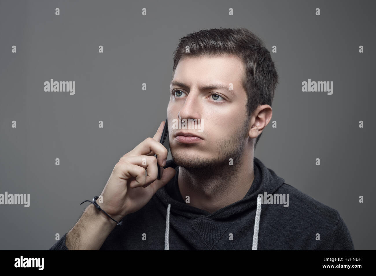 Portrait of young sporty serious man talking on the phone looking away ...