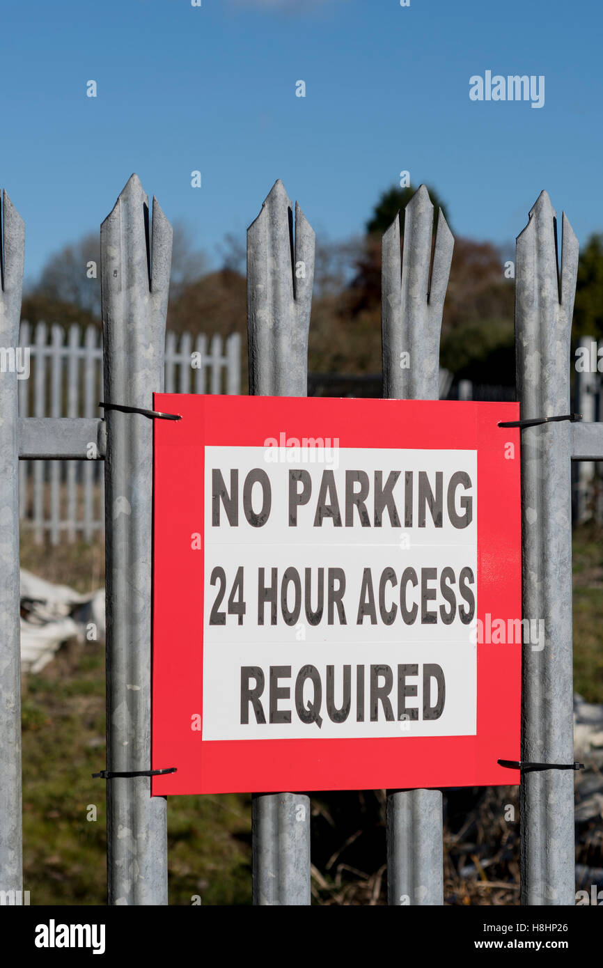 No Parking sign fixed to industrial metal fencing. No or limited access ...