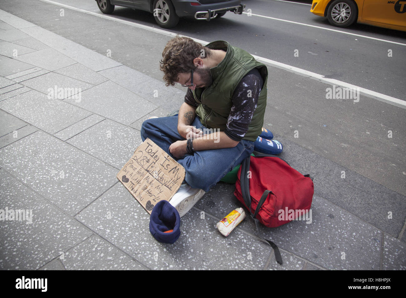 Homeless man sitting on the sidewalk reaching out for help along 7th ...
