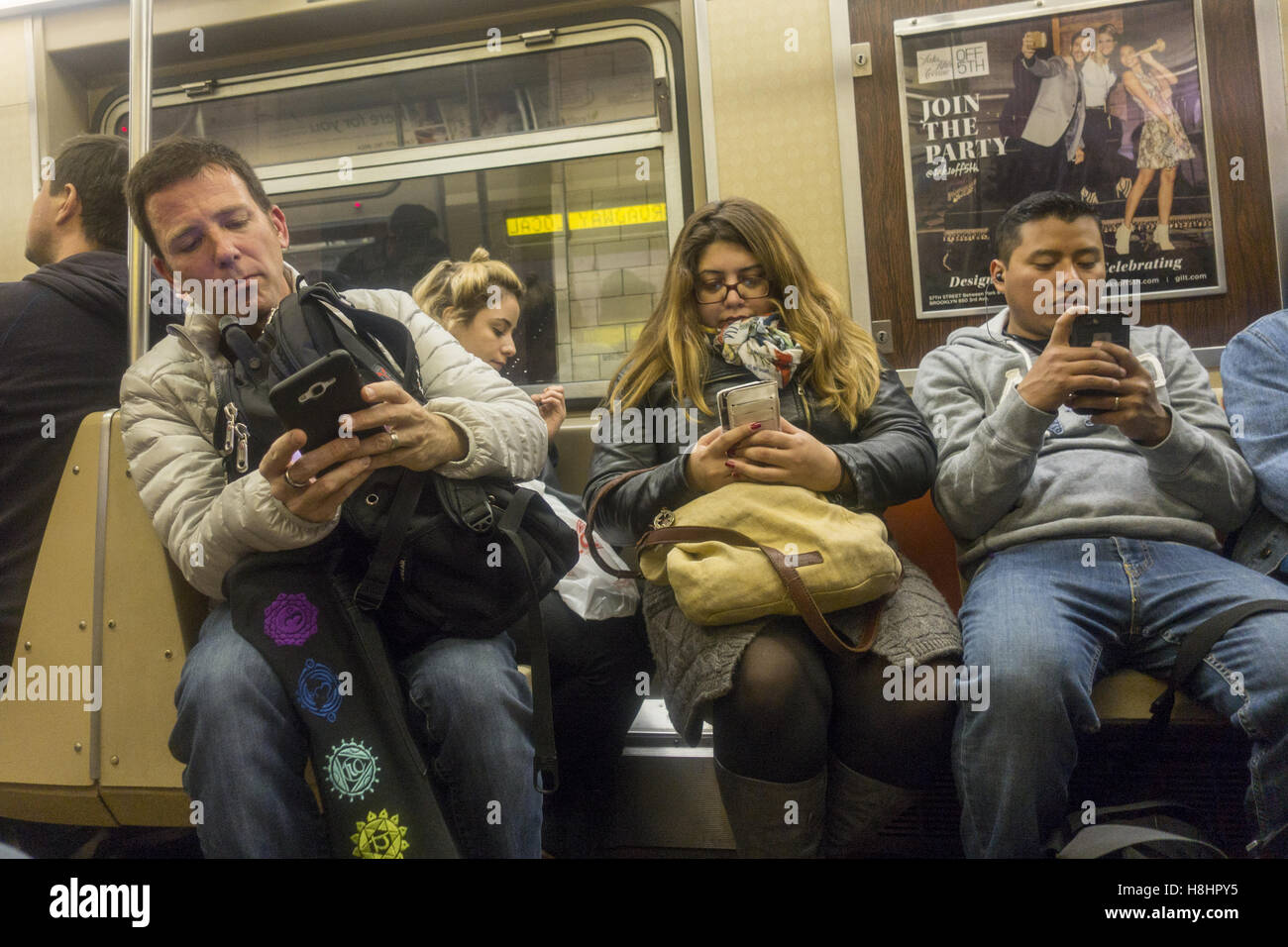 Subway riders use their cell phones on their way home from work in the ...