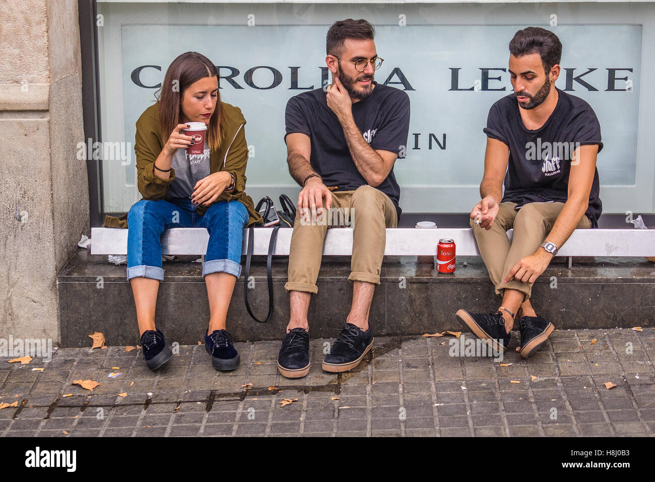 Three Spanish friends, one female and two males, sit in front of a ...