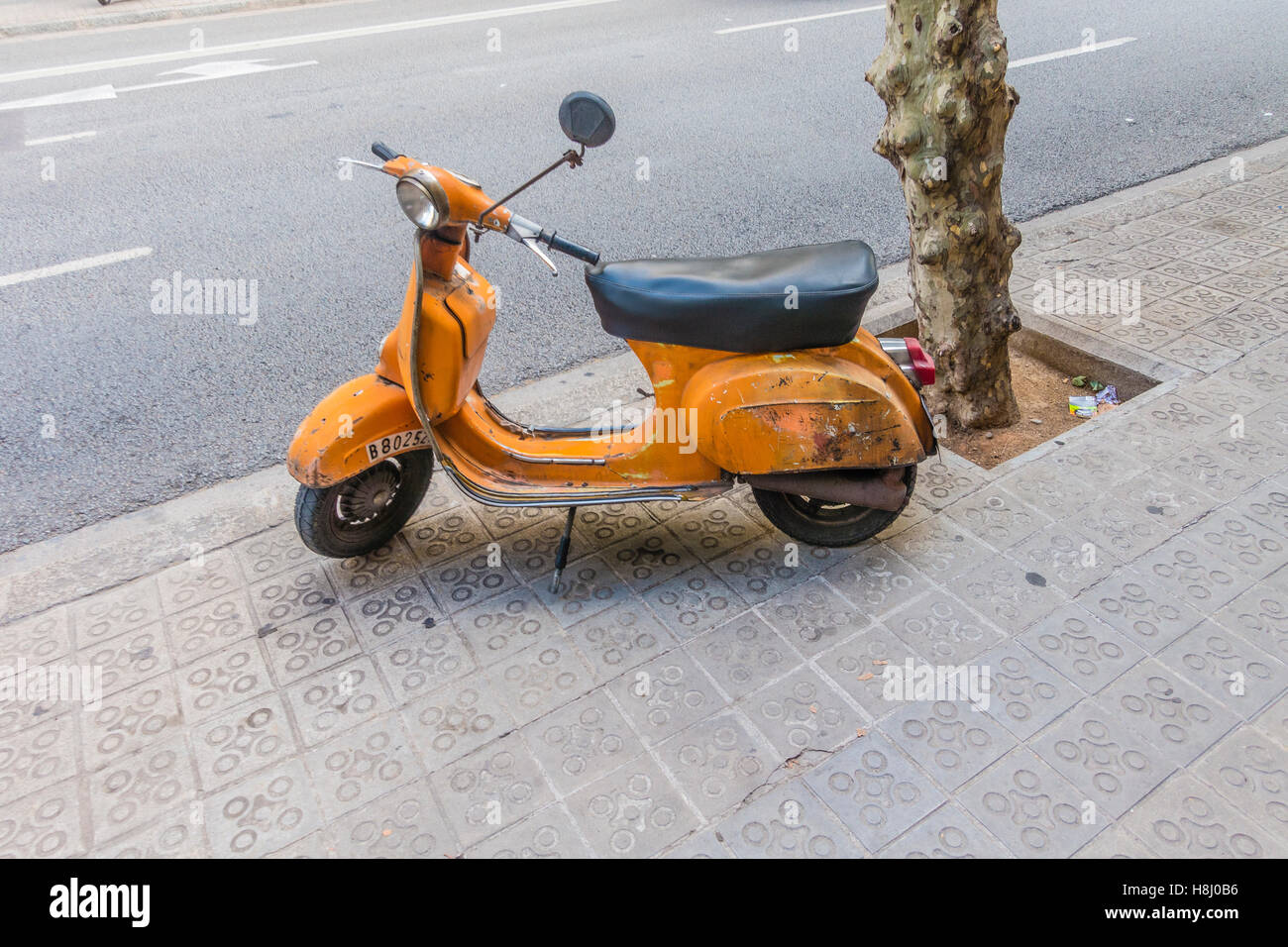 A very old orange and black Vespa Super motorscooter is parked on a ...