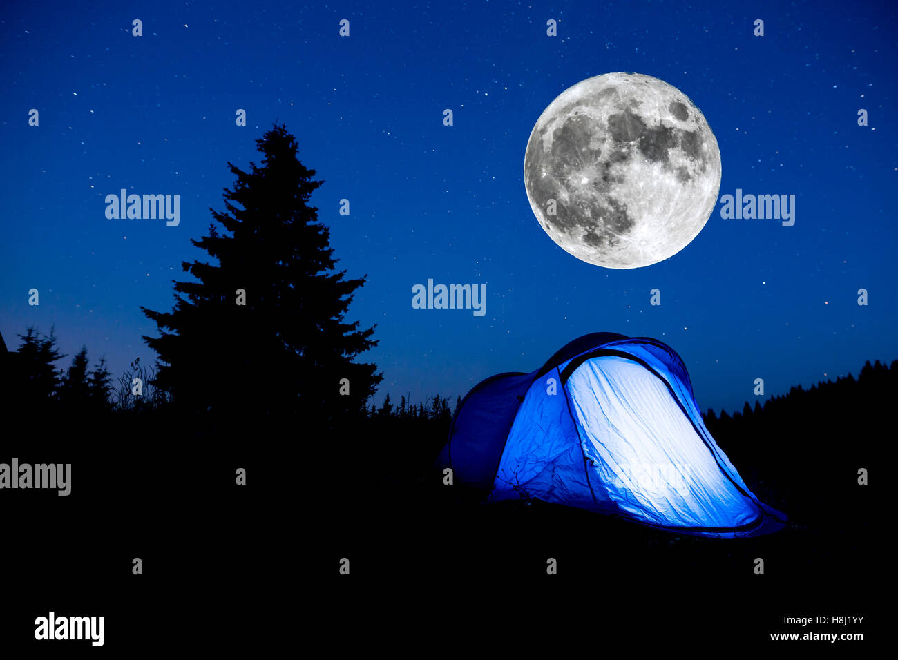 Super Moon. Blue illuminated tent with travelers in the mountain ...