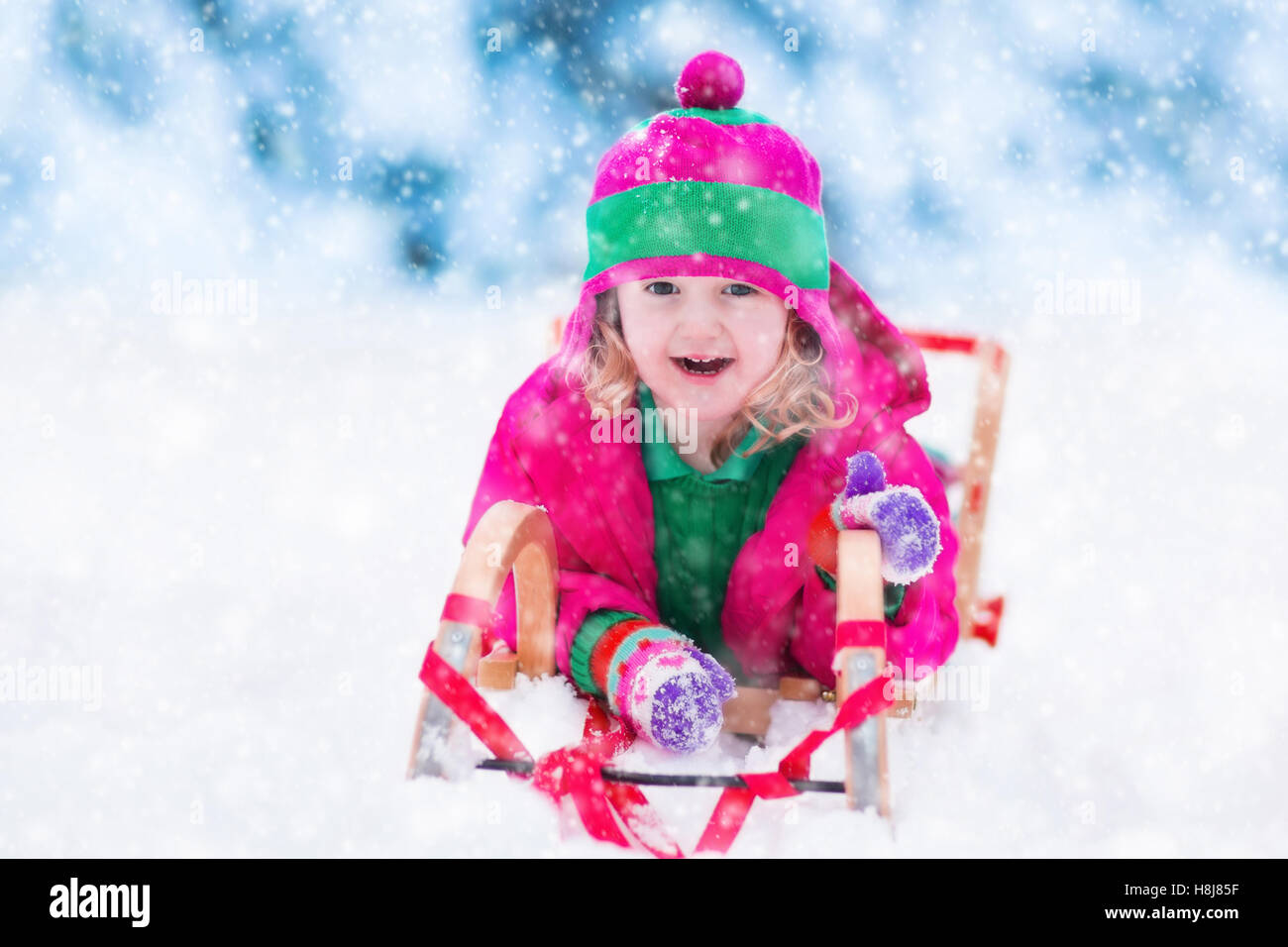 Little girl enjoying sleigh ride. Child sledding. Toddler kid riding a ...