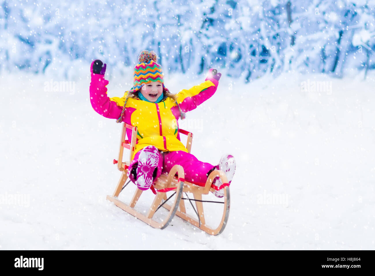 Little girl enjoying sleigh ride. Child sledding. Toddler kid riding a ...
