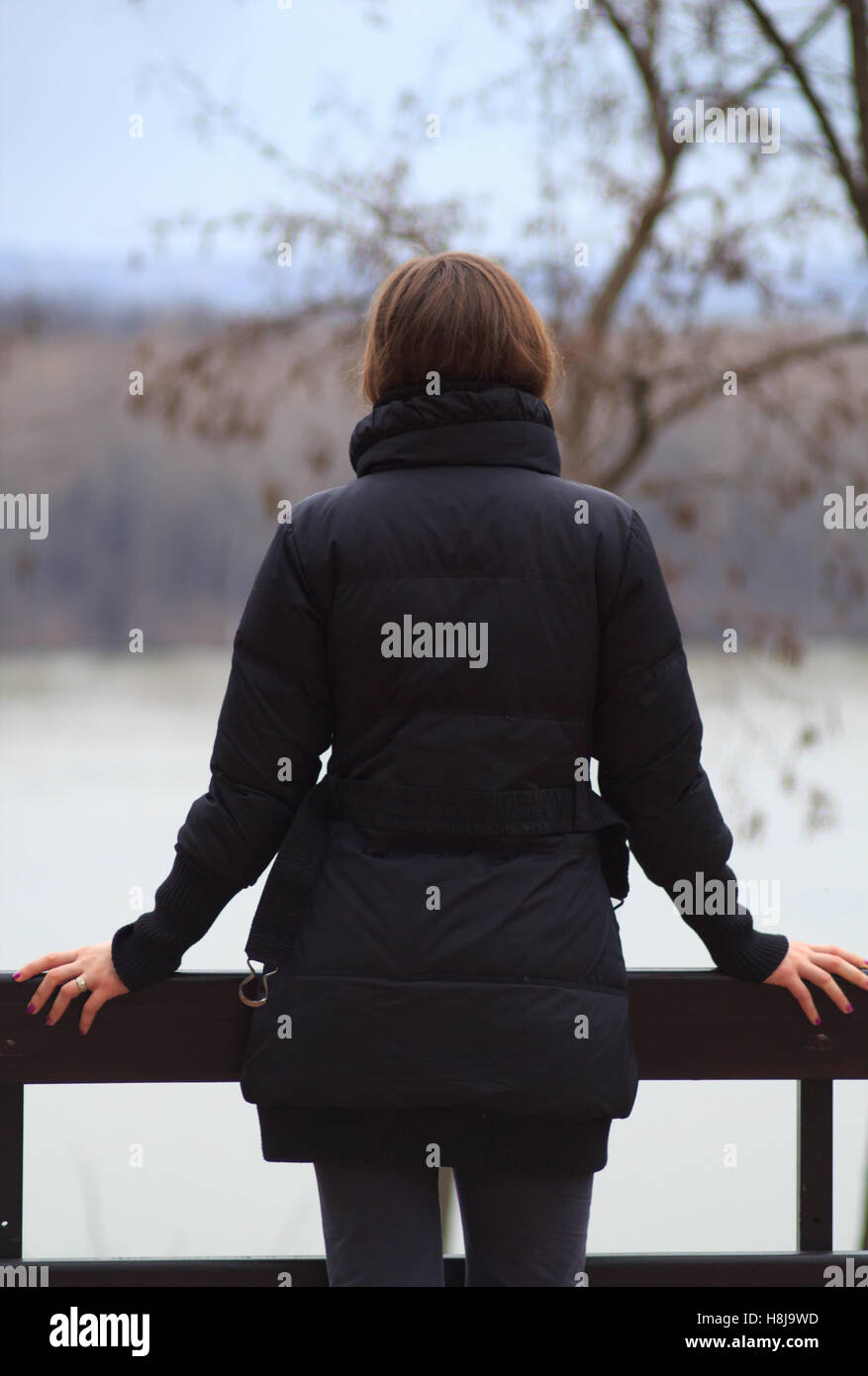 Unknown young woman standing alone thinking Stock Photo - Alamy