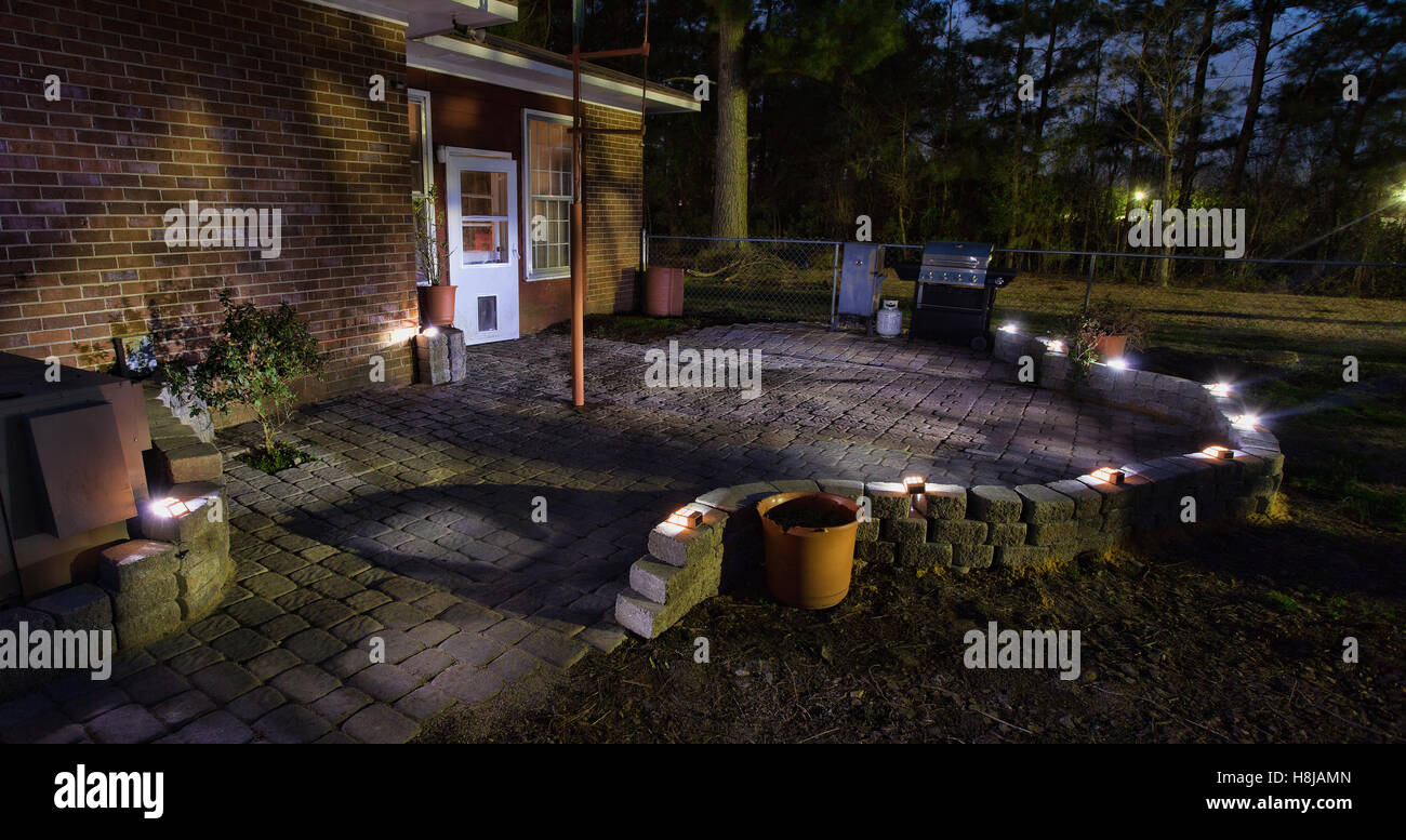 Sand set bricks on a patio with lights just after dark Stock Photo - Alamy