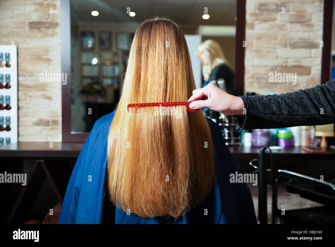 Hairdresser combs long hair of young woman Stock Photo - Alamy