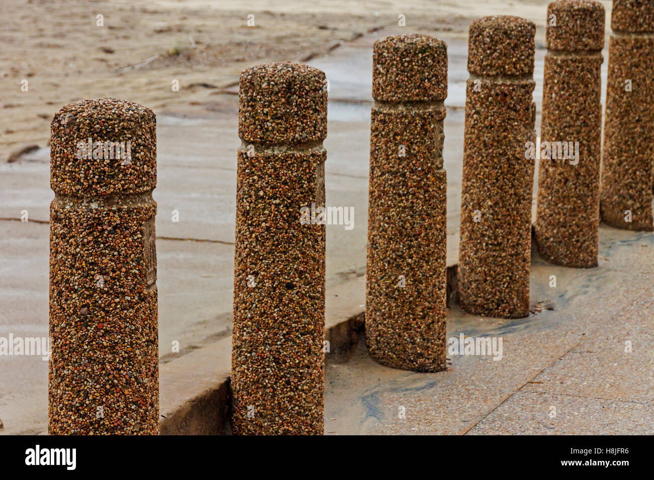 Textured barrier posts protecting beach pedestrian walkway on rainy ...