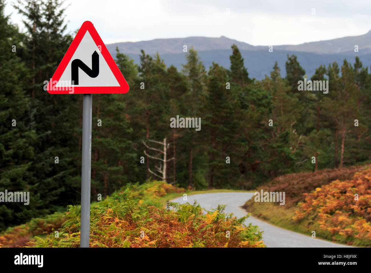 Triangular road sign warning of bends in the road Stock Photo - Alamy