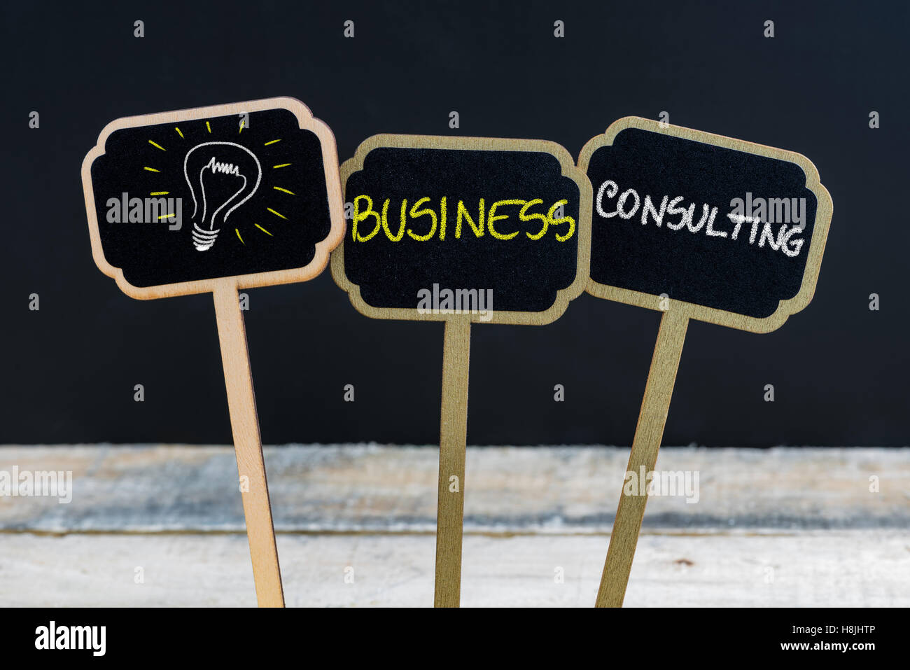 Concept message BUSINESS CONSULTING and light bulb as symbol for idea written with chalk on ...