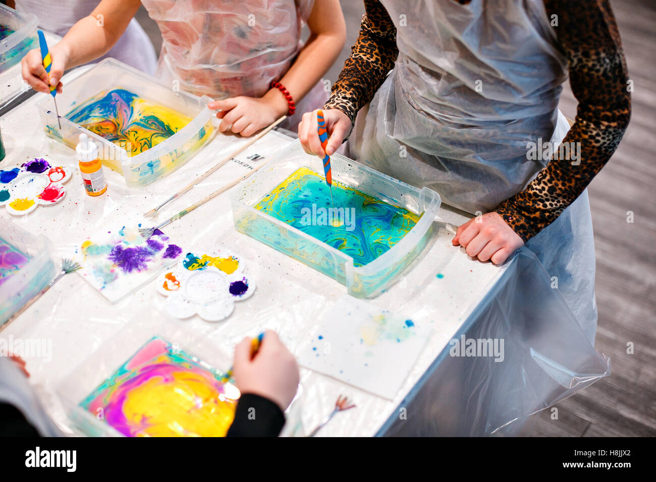 Child drawing with needle on the water. Ebru art is a method of aqueous ...