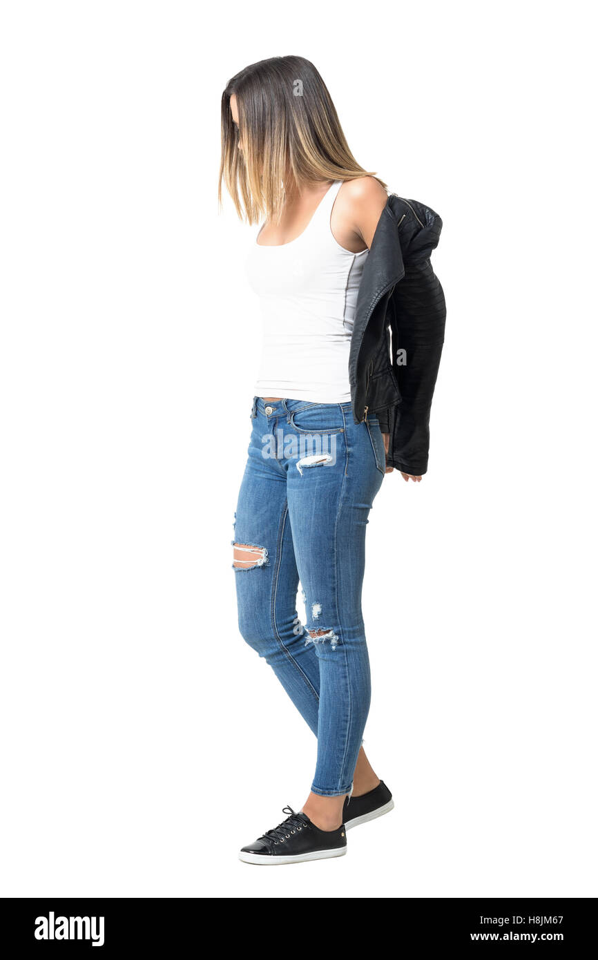 Young woman in tank top and ripped jeans taking off leather jacket ...