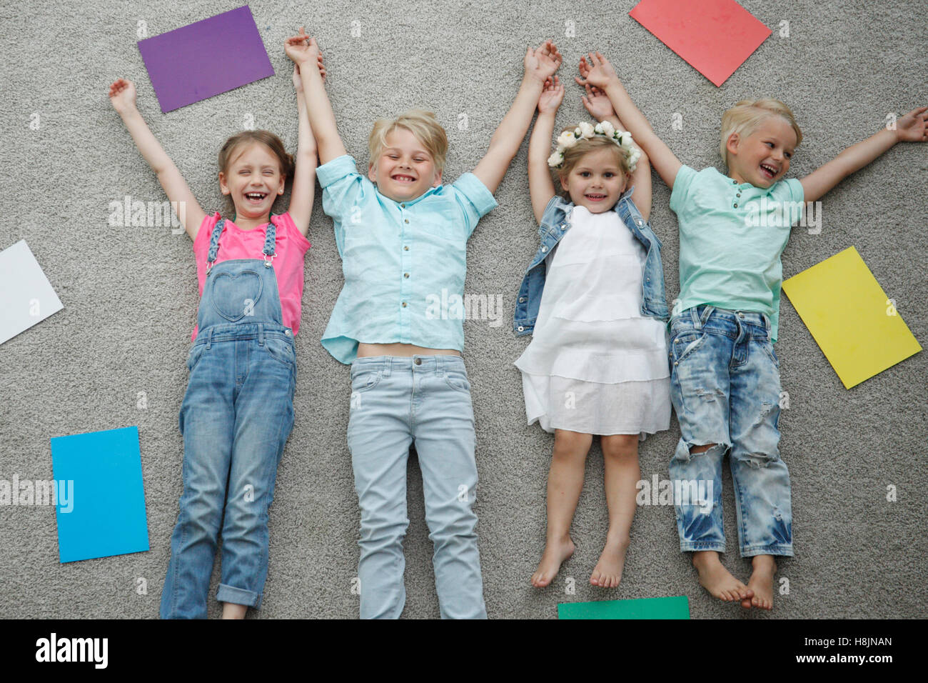 Four happy children laying on floor and smiling among colorful paper ...