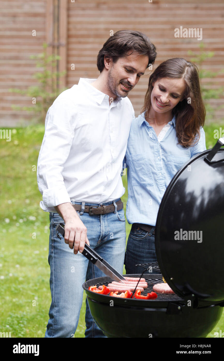 Happy couple cooking food on barbecue Stock Photo - Alamy