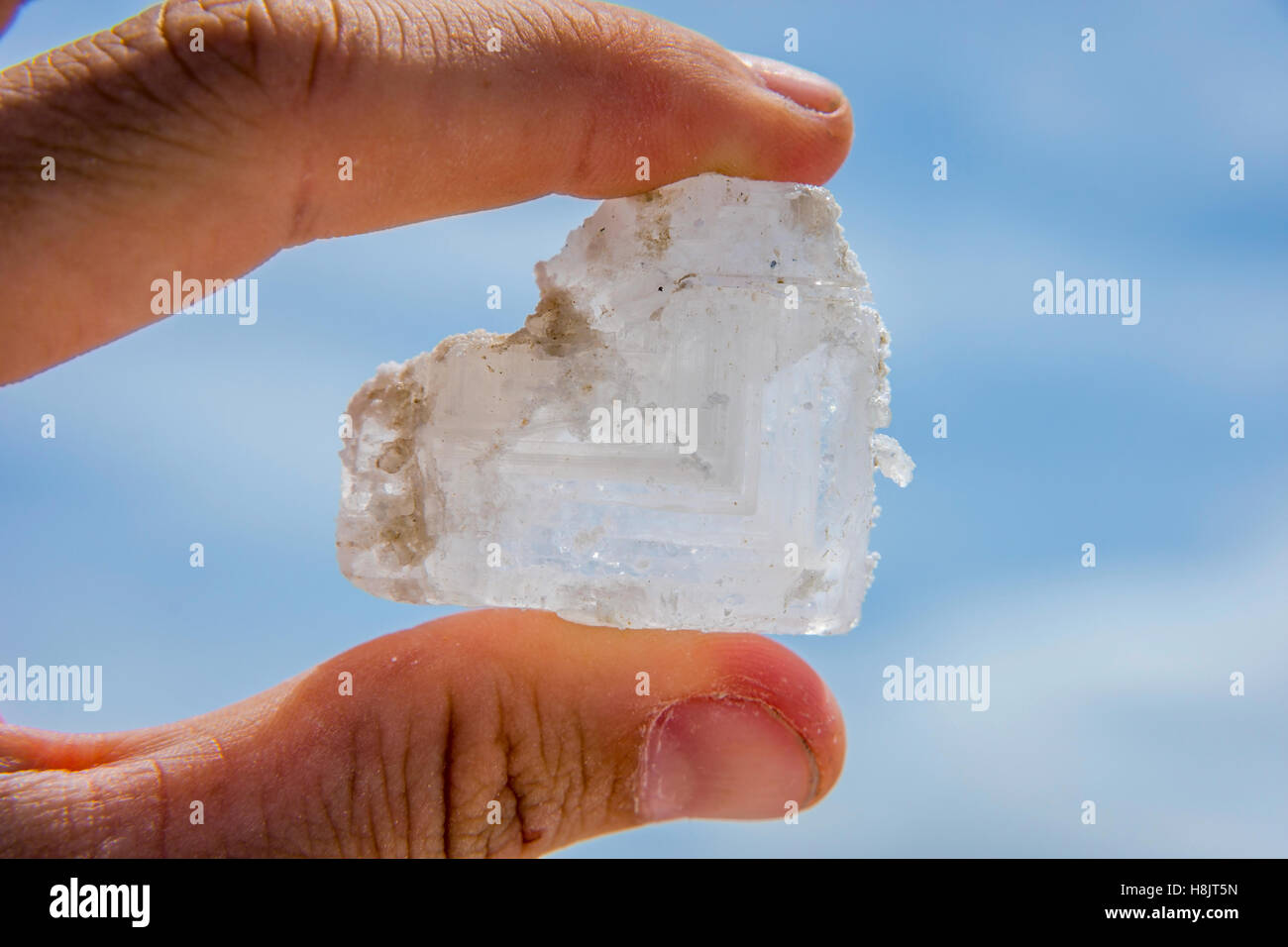 Holding big salt crystal in hand against blue sky Stock Photo - Alamy