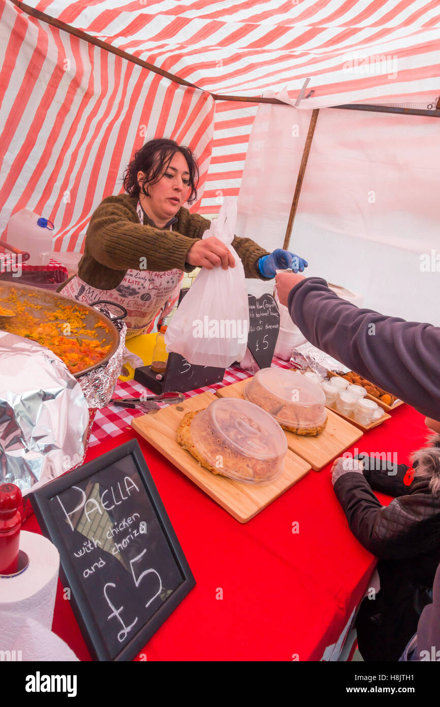 A Spanish woman stall holder at a UK farmer's market serving a customer ...