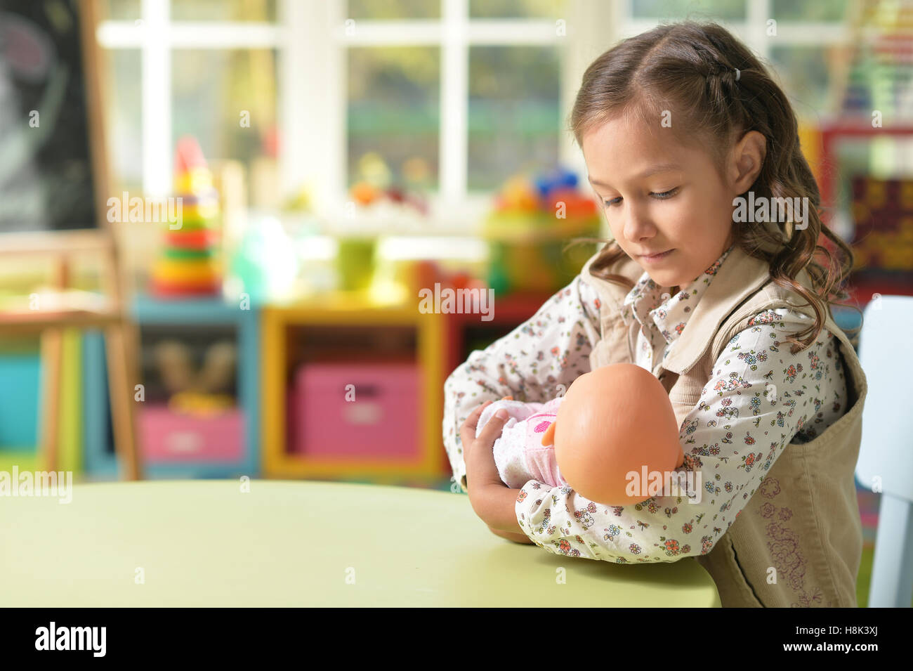 Girl playing with baby doll Stock Photo - Alamy
