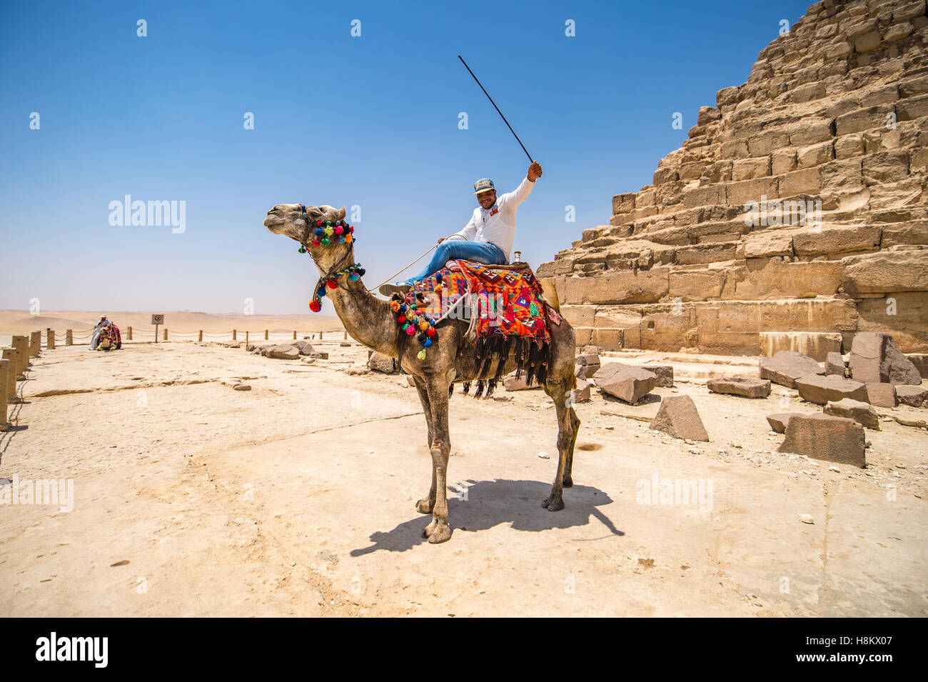 Cairo, Egypt Camel and its rider resting in the desert beside ruble at the base of one of the ...