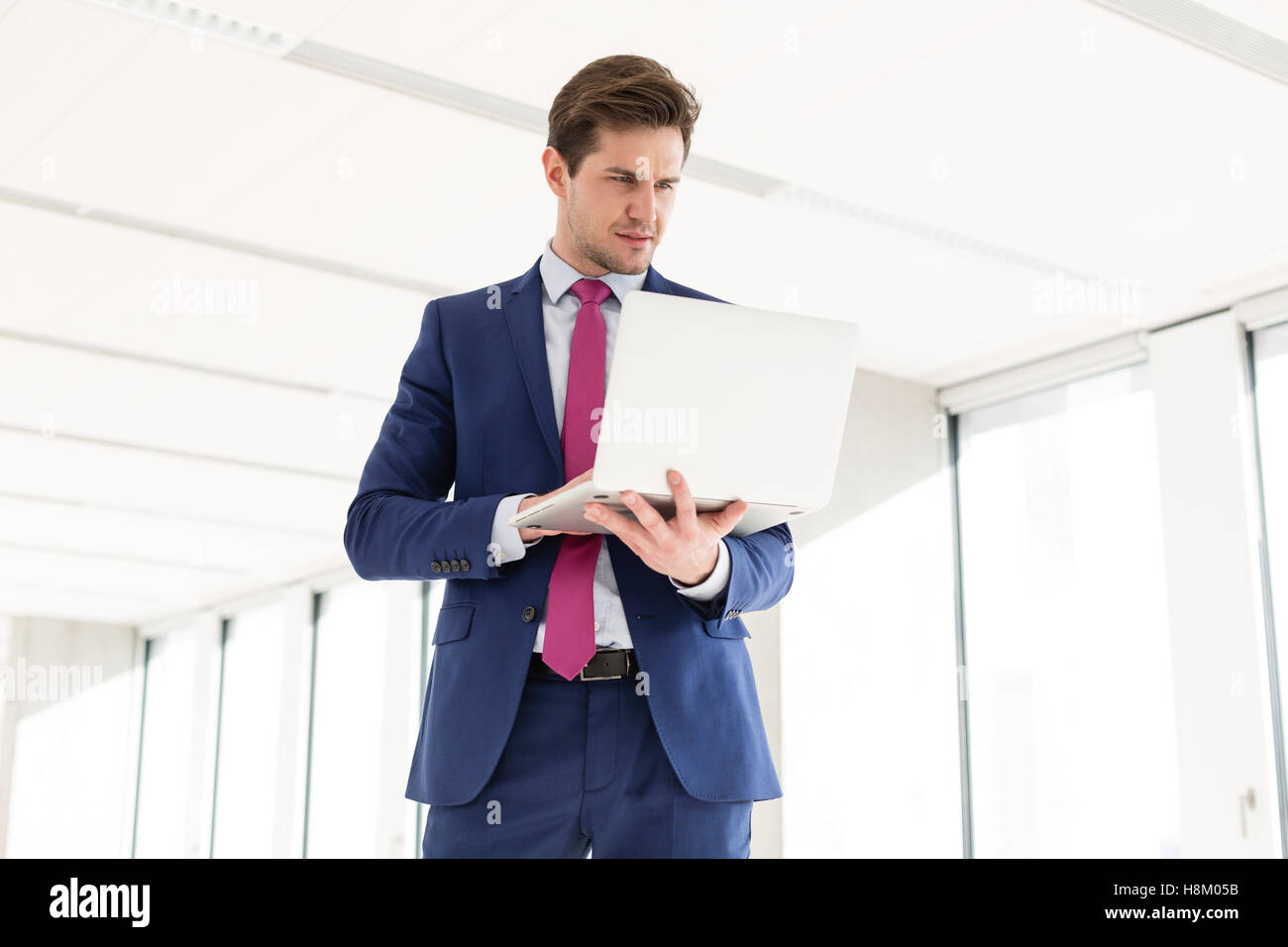 Young businessman using laptop in new office Stock Photo - Alamy