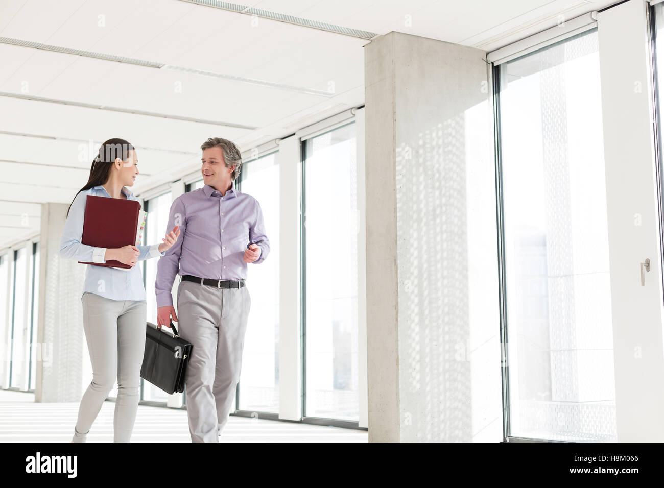 Businessman and businesswoman talking while walking in new office Stock ...