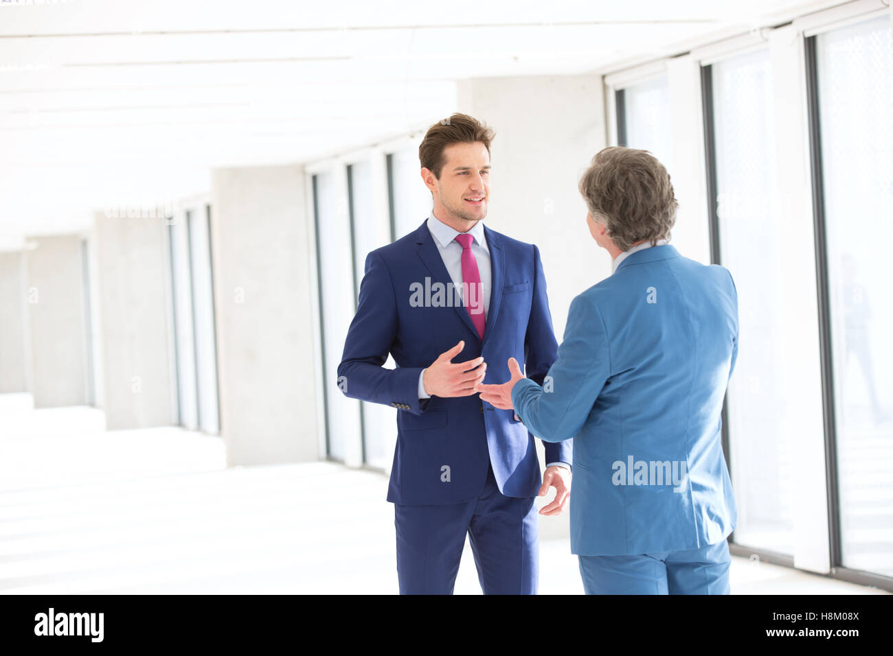 Young businessman talking with male colleague in new office Stock Photo ...