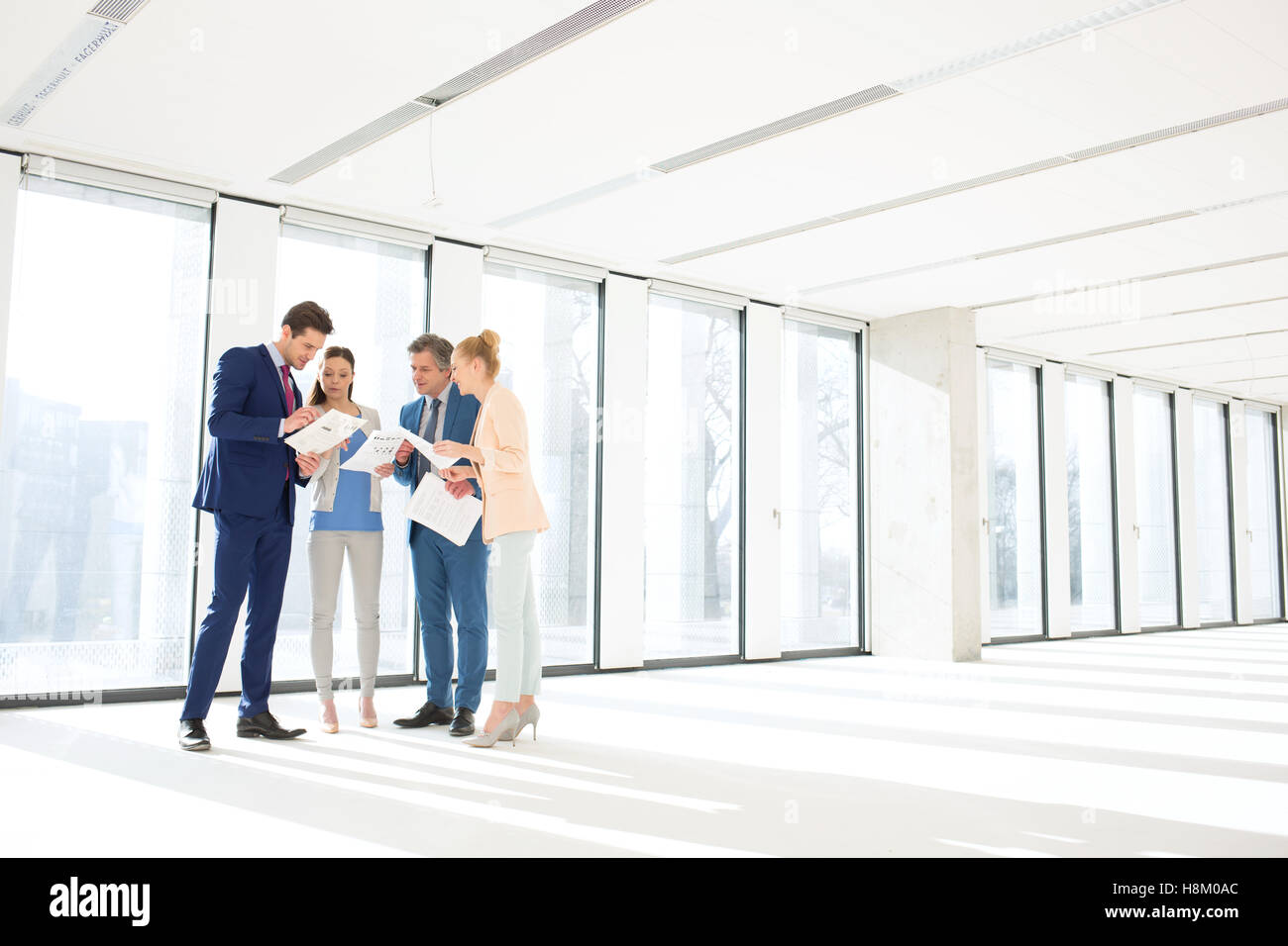 Full length of business people reviewing documents in new office Stock ...