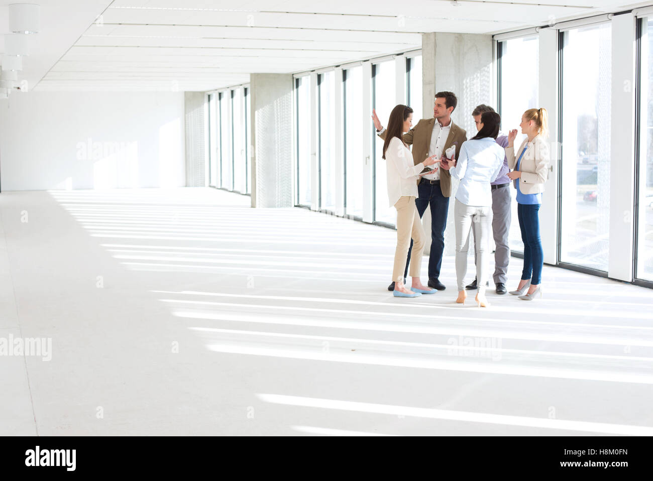 Full length of business people having discussion in empty office space ...