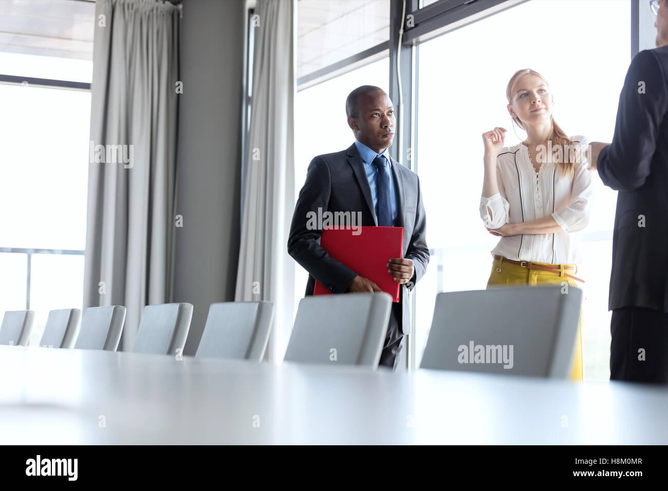 Business people having discussion while standing by conference table in ...